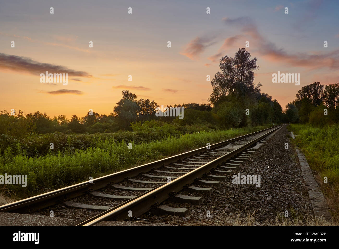 Railroad tracks infront of beautiful nature scenery and the sunset in ...