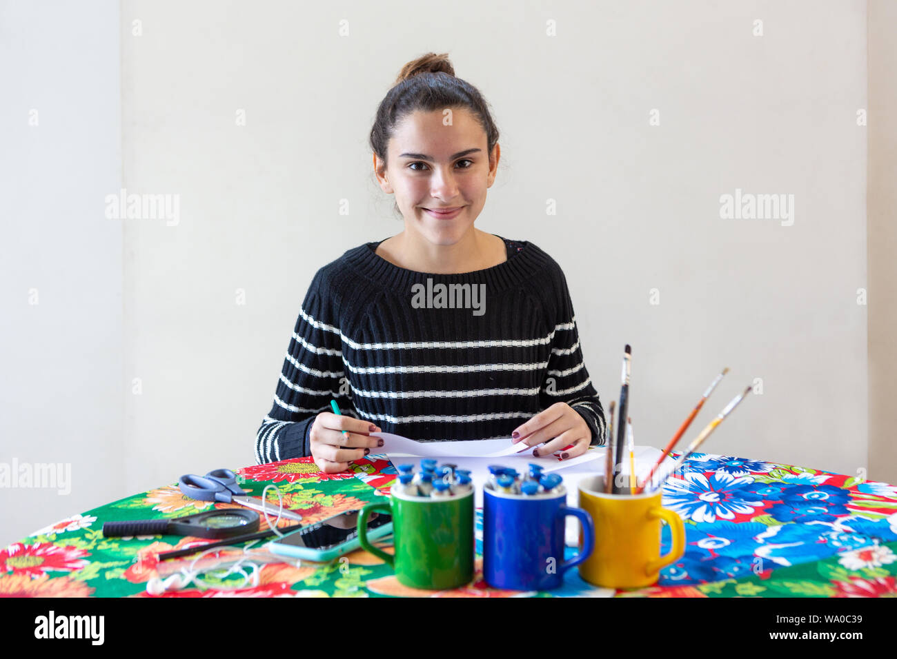 Young talented woman artist sitting at the table with flowered ...