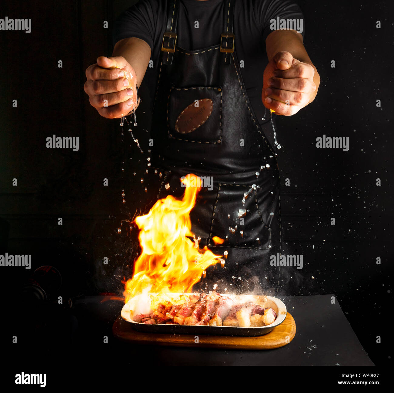 Chef sprinckles lemon juice on flambe meat while cooking a dish. Low ...