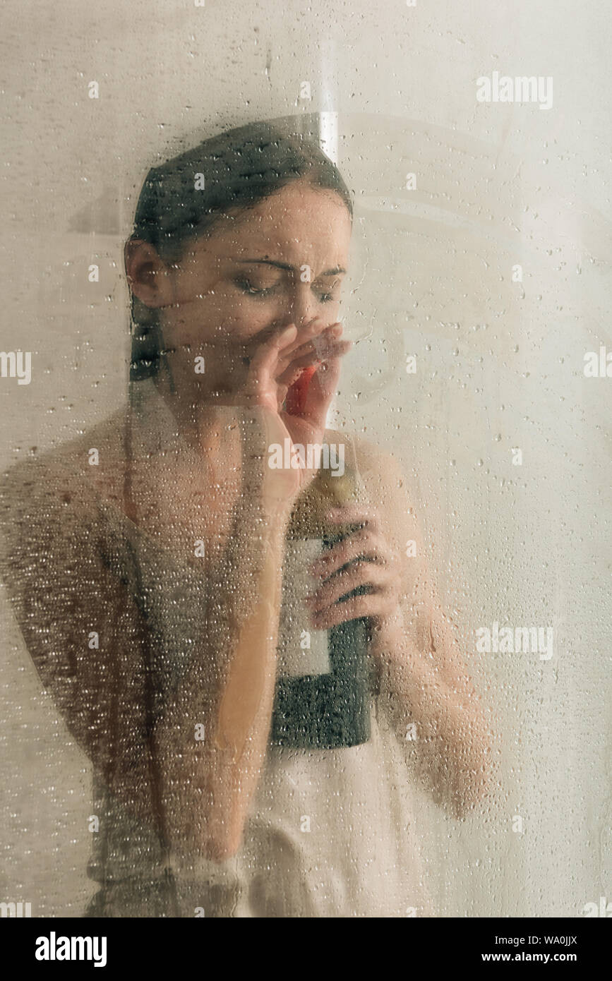 lonely depressed woman in shower with wine bottle at home Stock Photo ...