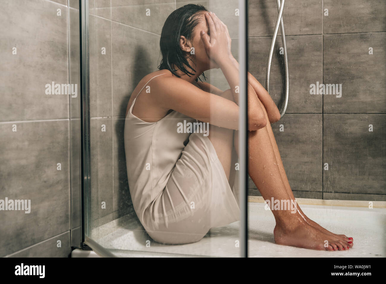 sad depressed woman covering face while sitting in shower at home Stock ...