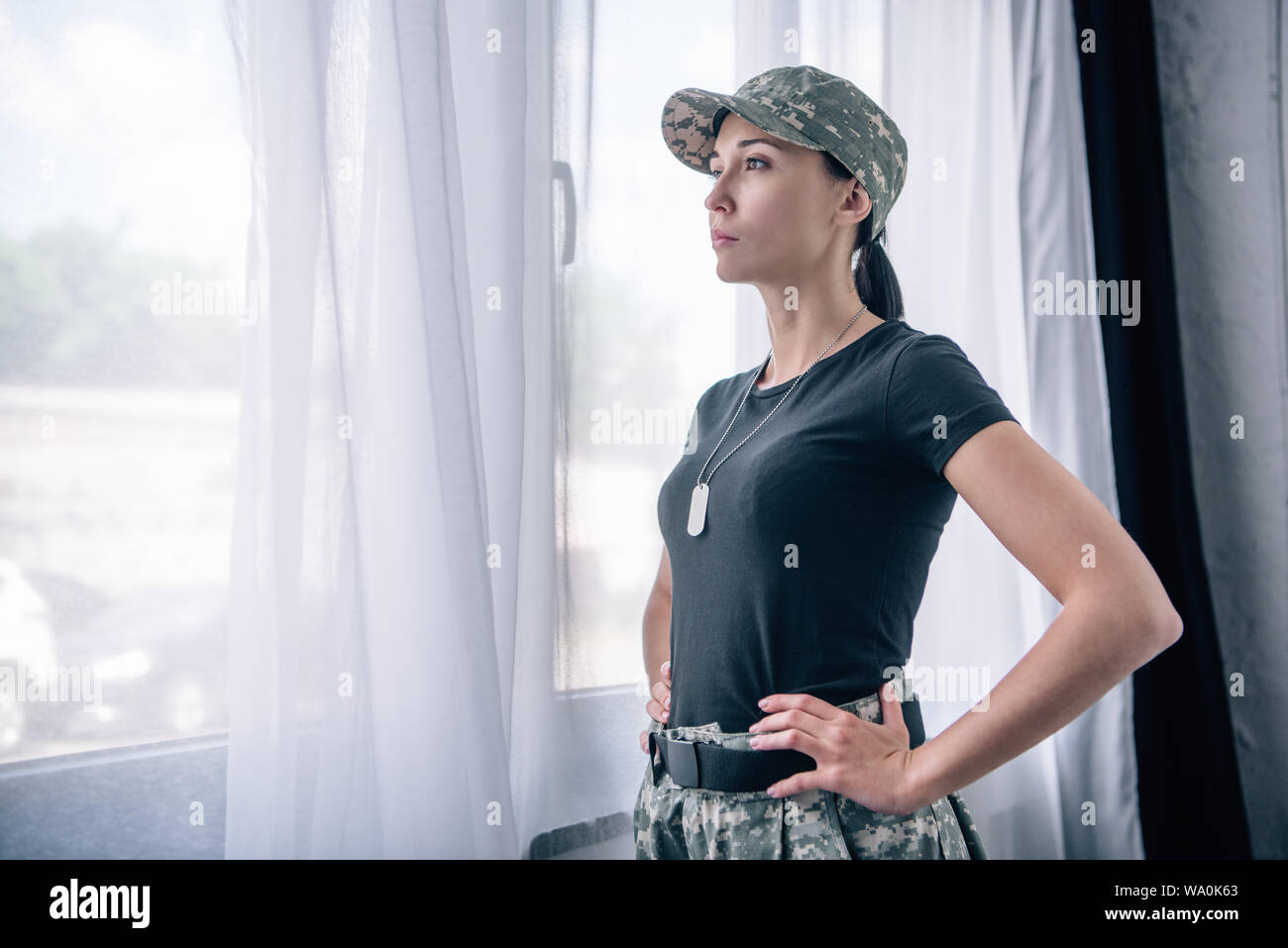 beautiful woman with hand on hip in military uniform at home with copy ...