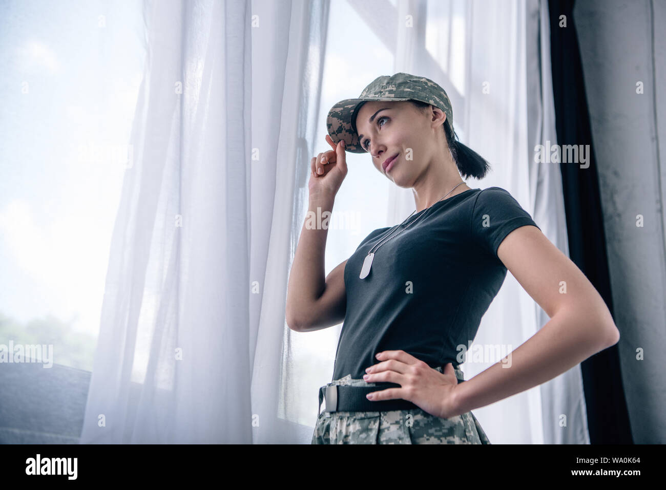 beautiful woman with hand on hip in military uniform at home with copy ...