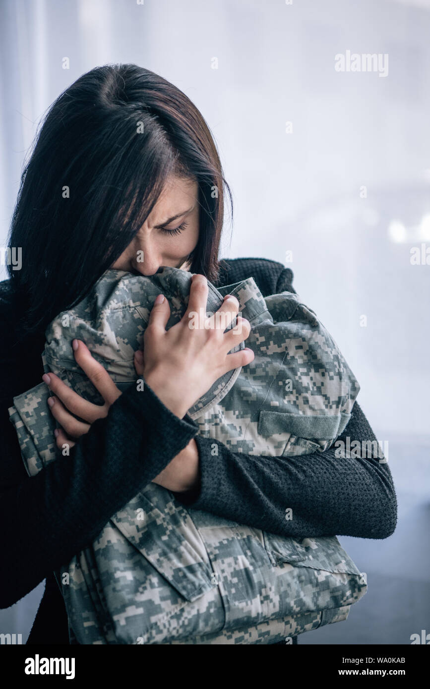 depressed woman crying and holding military clothing at home Stock ...