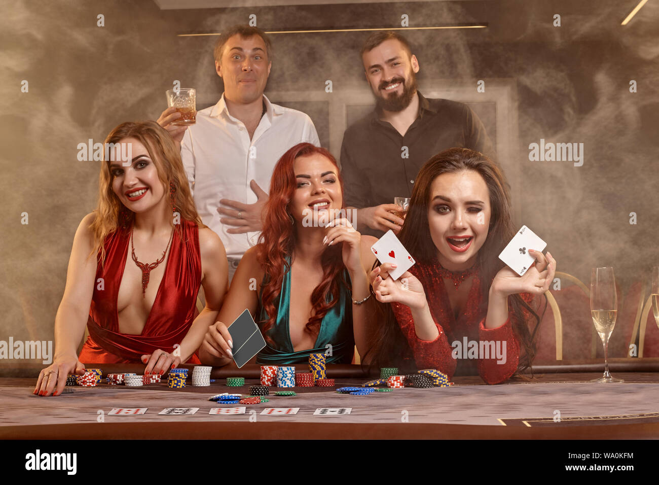 Joyful buddies are playing poker at casino. They are celebrating their ...