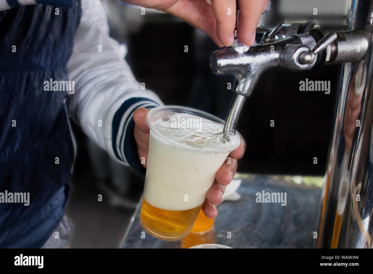 Man pours draft beer in plastic glass during picnic. Close up image ...