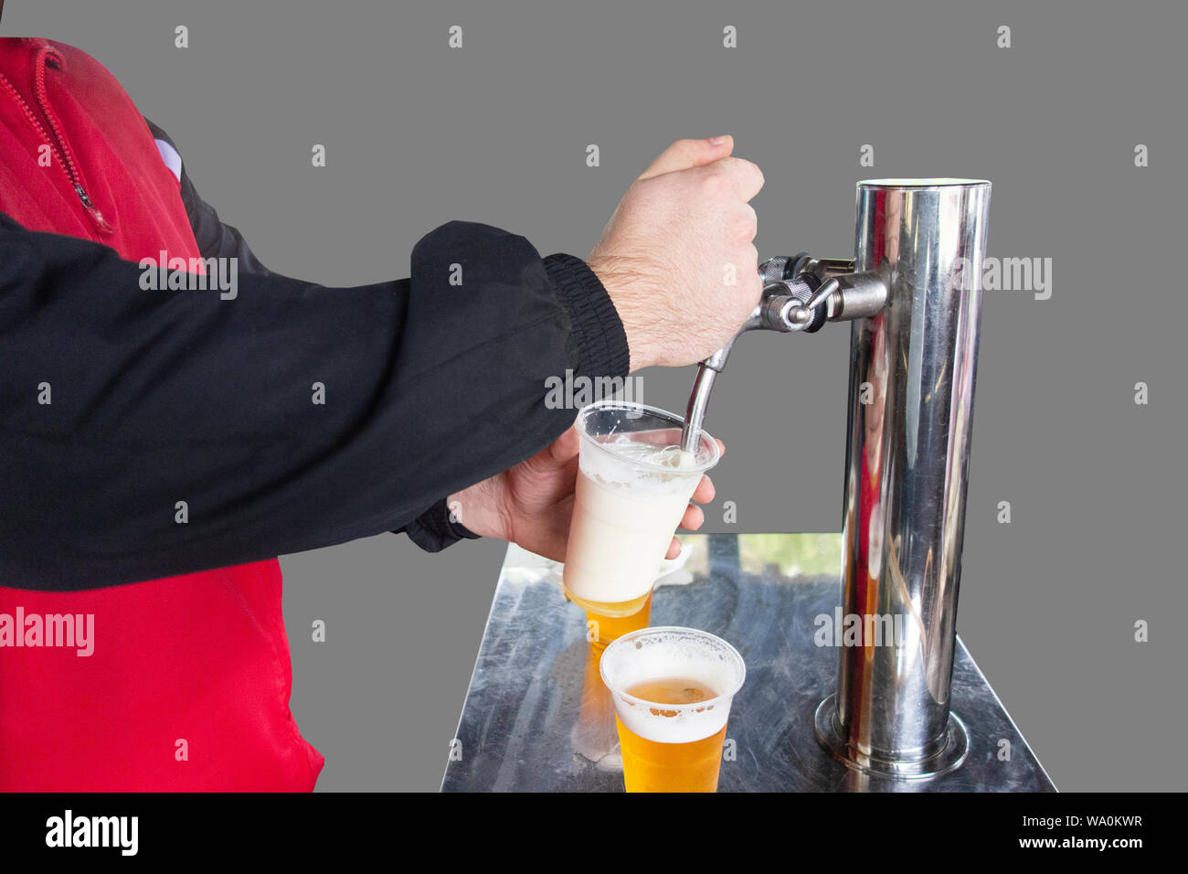Man pours draft beer in plastic glass during picnic. Close up isolated ...
