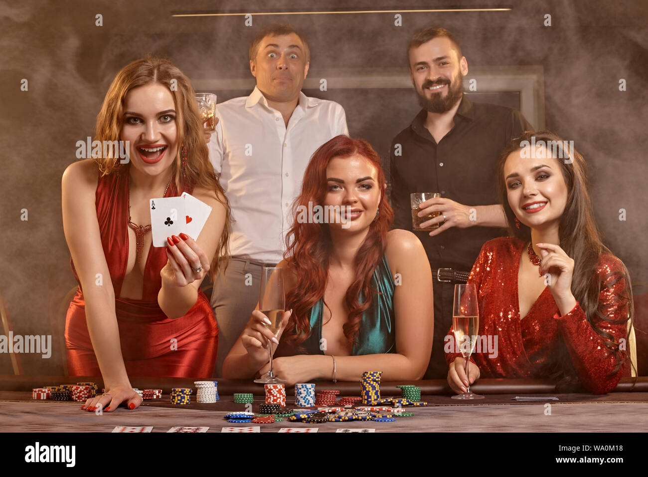 Happy classmates are playing poker at casino. They are celebrating ...