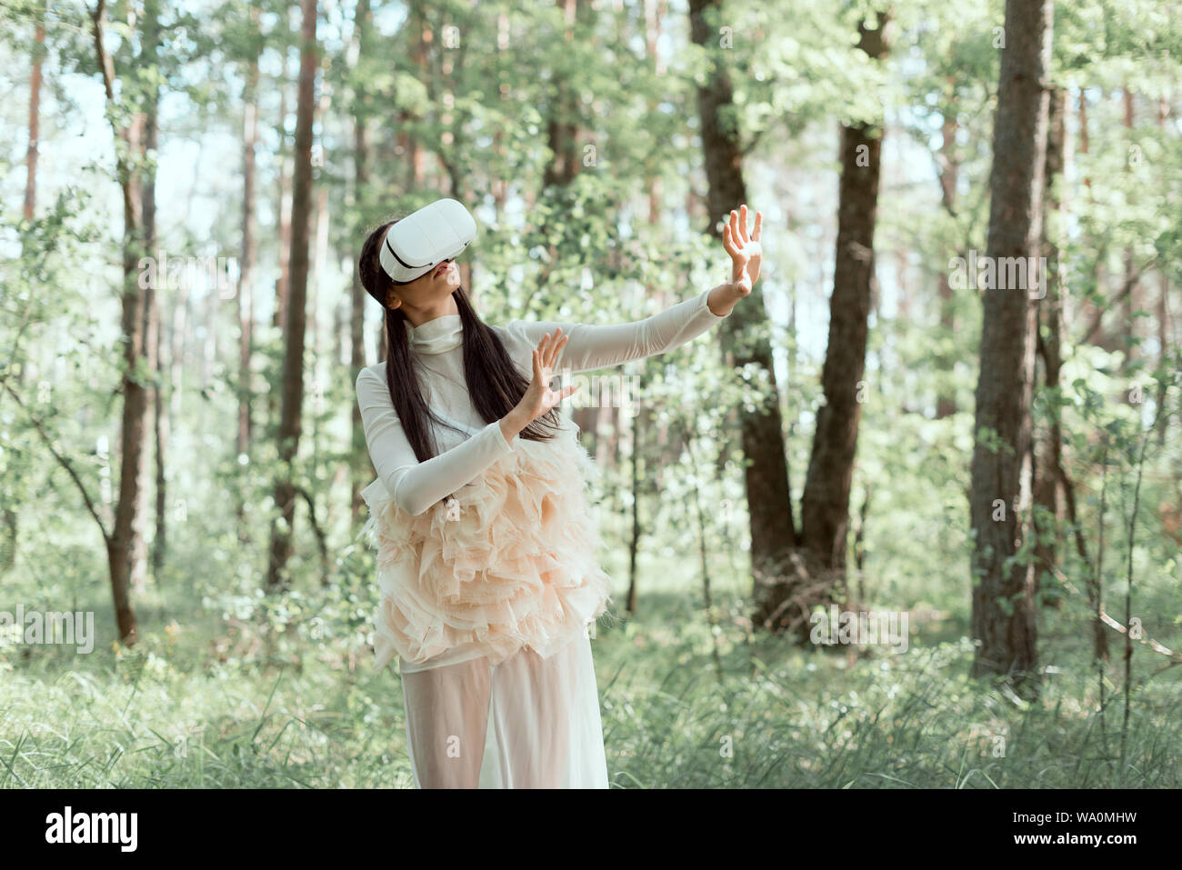 tender woman in white swan costume and vr headset standing on forest ...