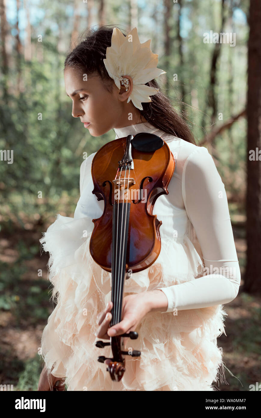 tender woman in white swan costume standing on forest background with ...