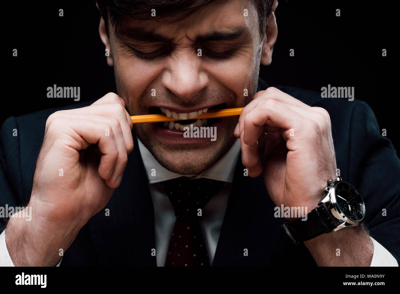 angry businessman biting pencil isolated on black Stock Photo - Alamy