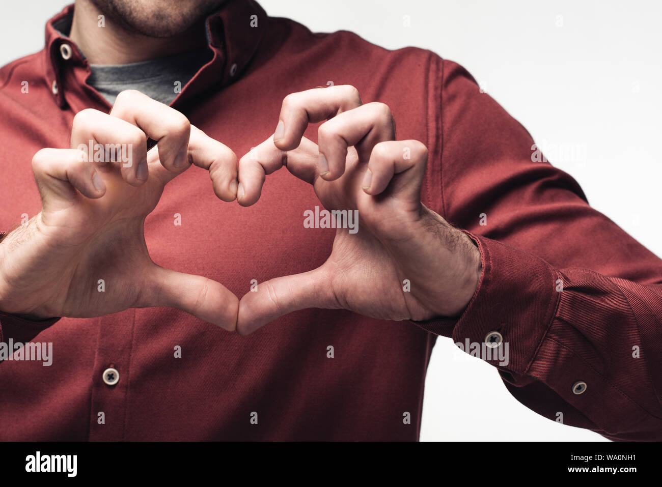 partial view of man showing heart sign with hands isolated on grey ...