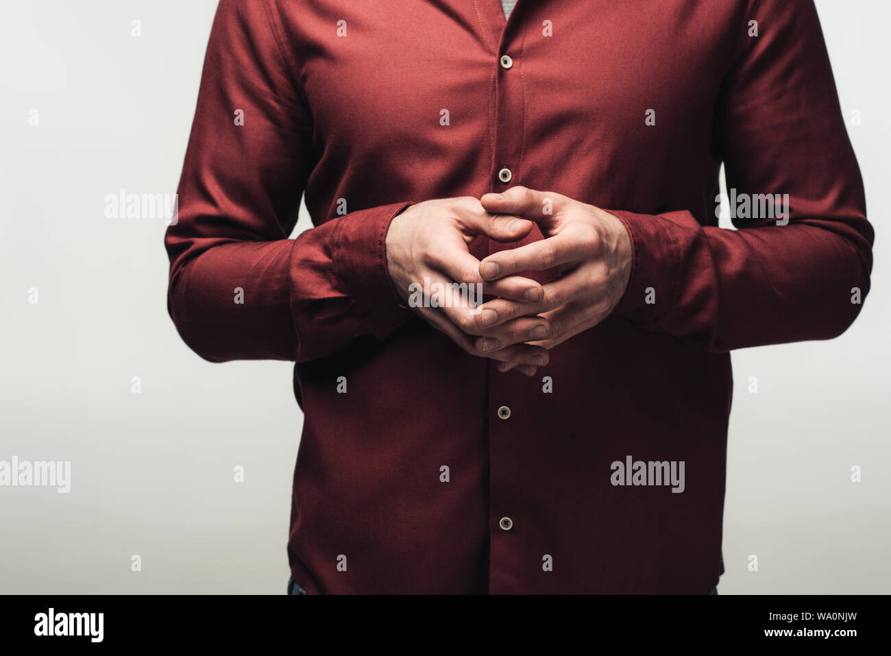 partial view of man standing with clenched hands isolated on grey ...