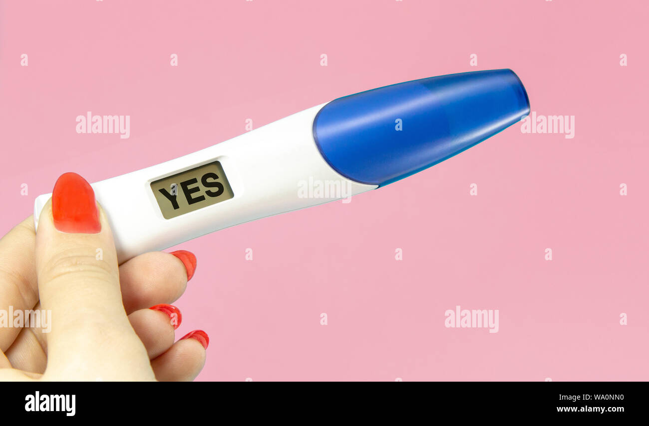 Woman hand holding digital pregnancy test isolated on pink background ...