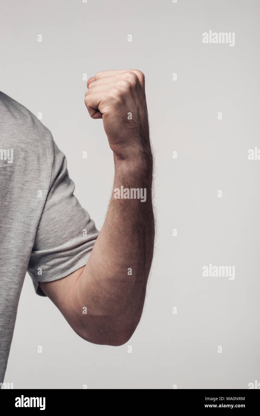 partial view of man showing fist isolated on grey, human emotion and ...