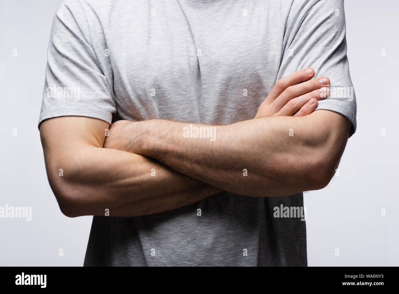 cropped view of man standing with crossed arms isolated on grey, human ...
