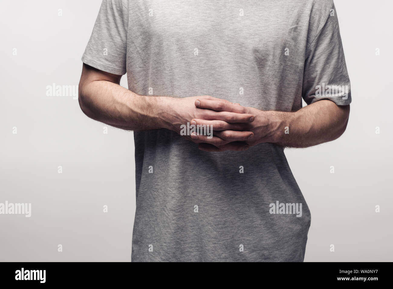partial view of man holding clenched hands isolated on grey, human ...