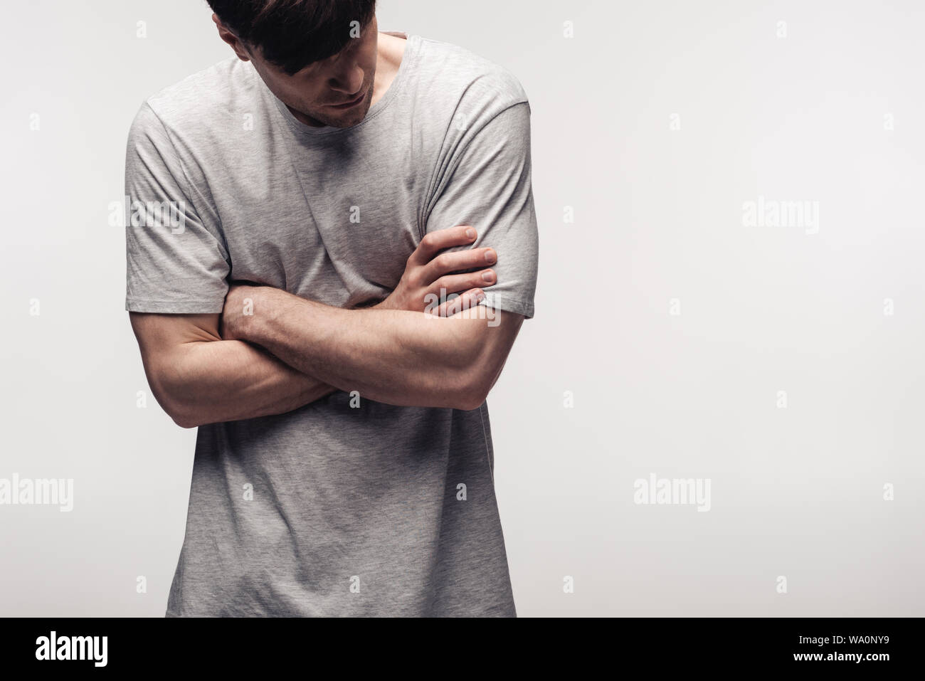 displeased young man standing with crossed arms isolated on grey, human ...