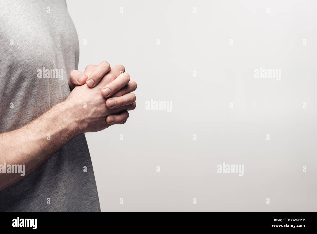 partial view of man holding clenched hands isolated on grey, human ...