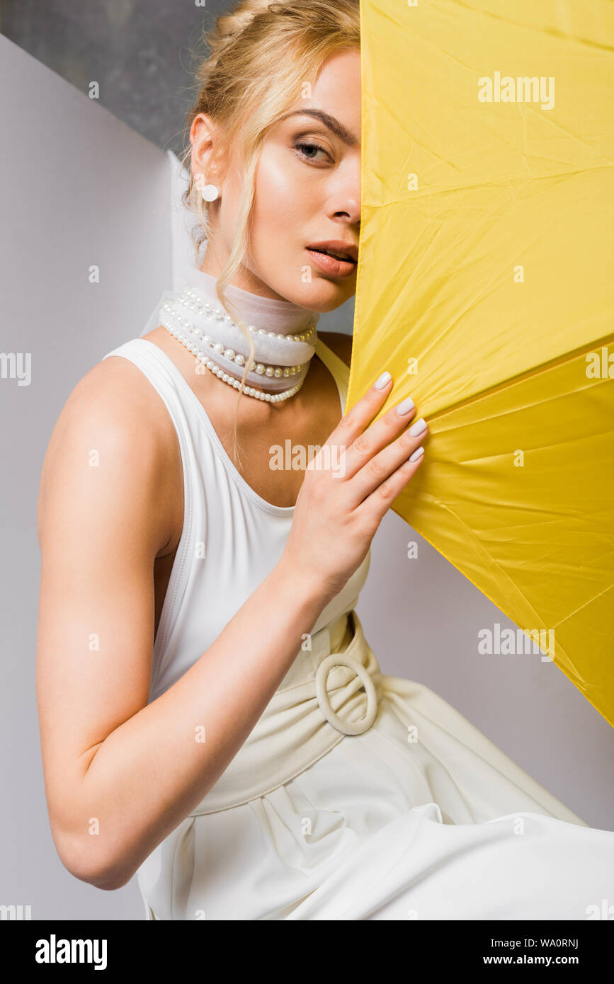 blonde woman covering face with yellow umbrella on white Stock Photo ...