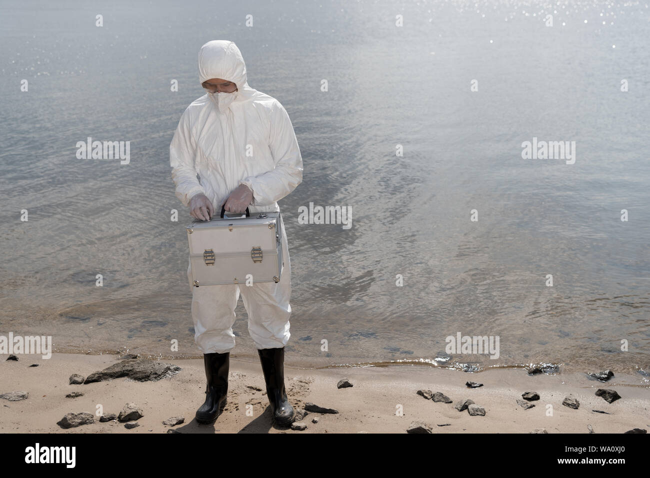 full length view of water inspector in protective costume holding ...