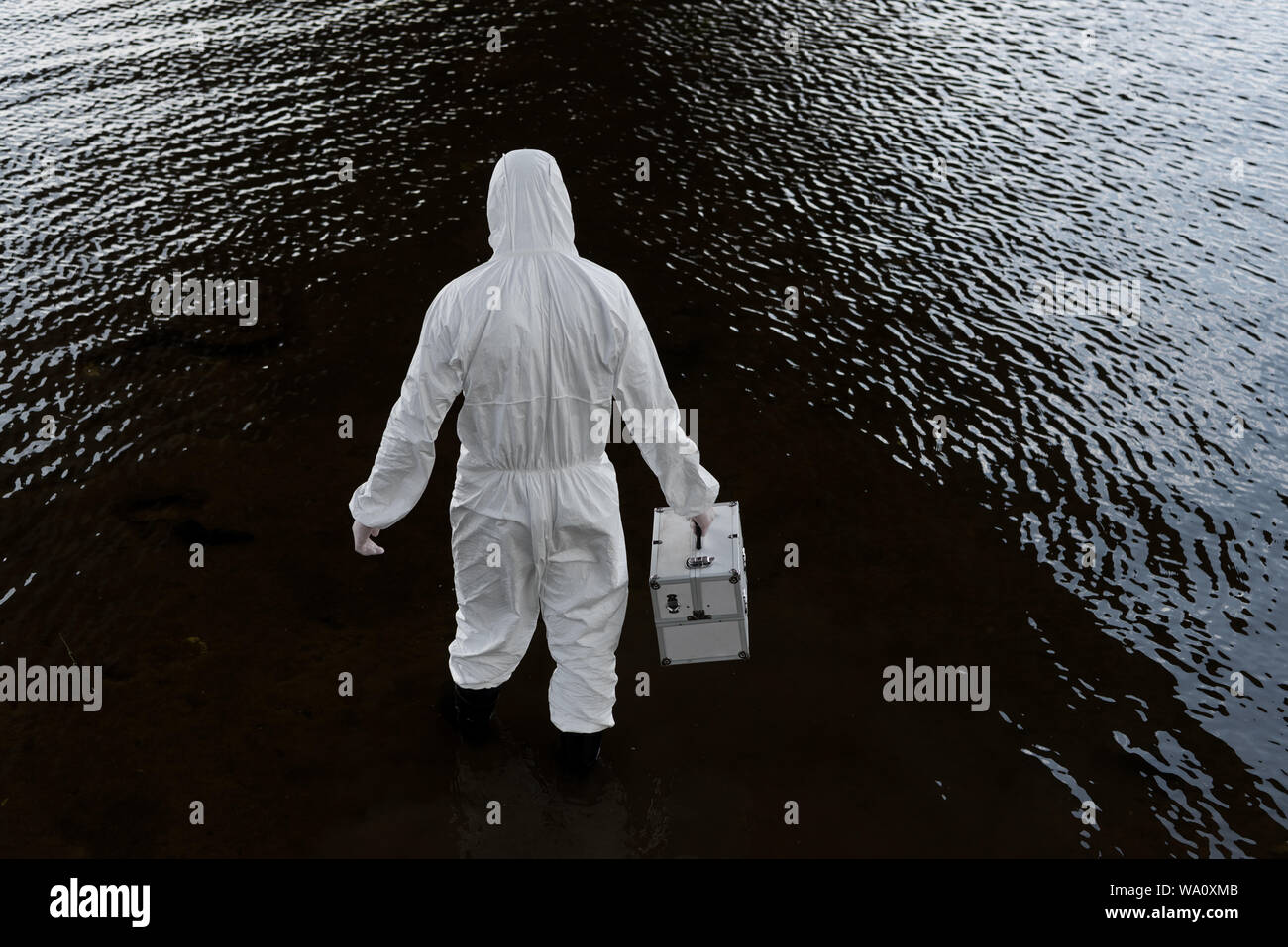 back view of water inspector in protective costume holding inspection ...