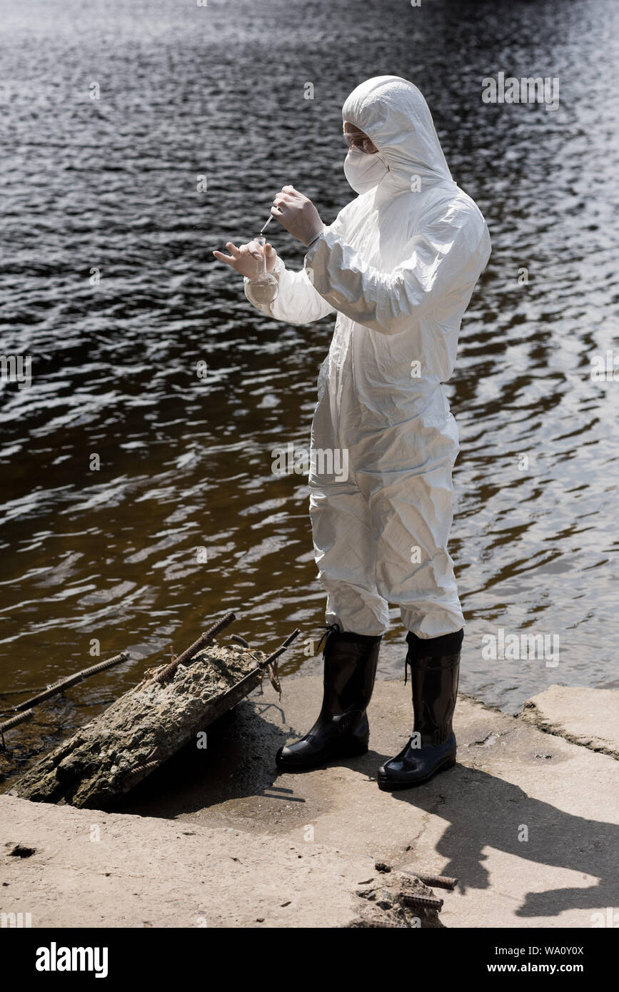full length view of water inspector in protective costume, latex gloves ...