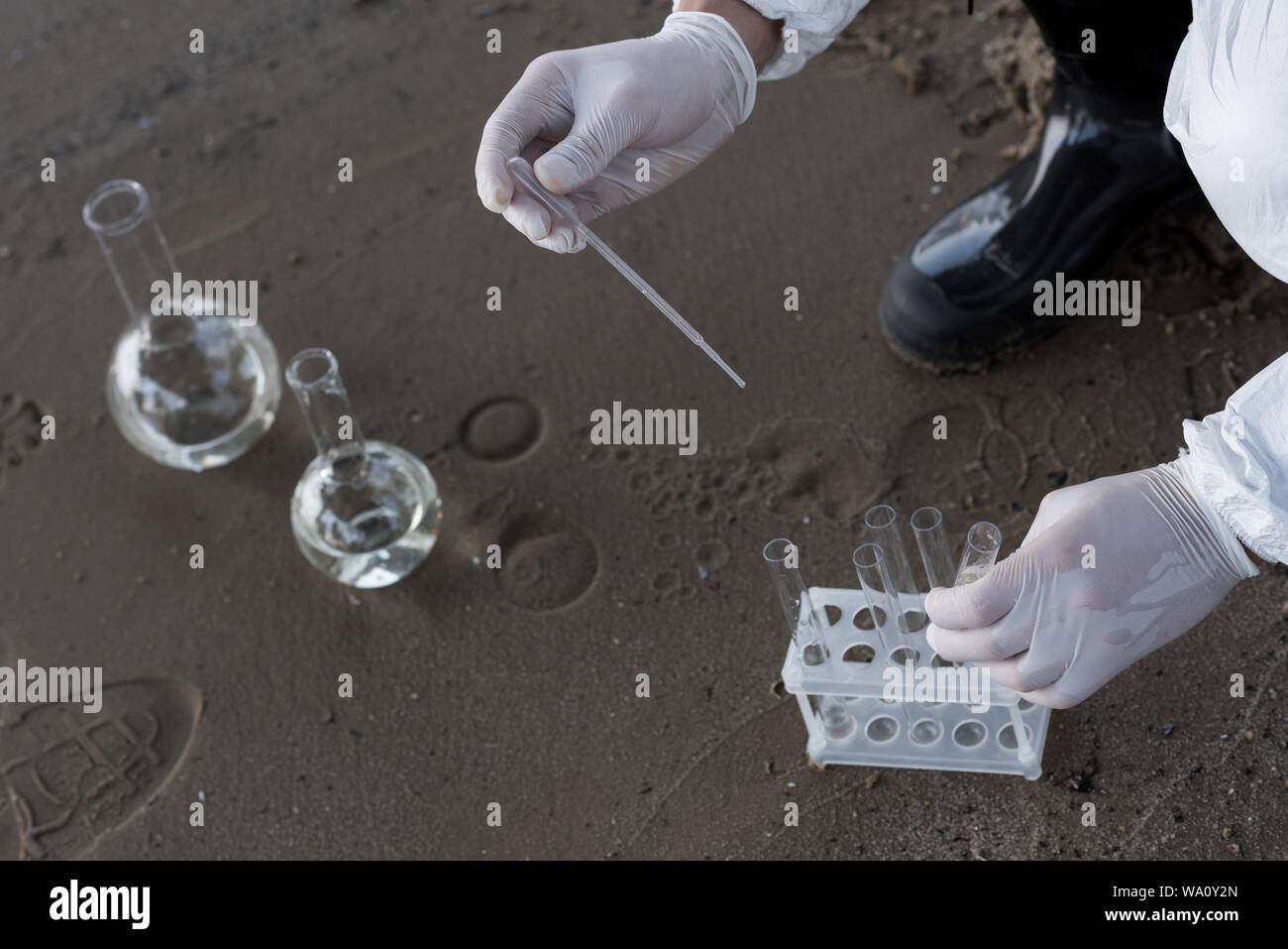 partial view of water inspector in latex gloves taking water samples at ...