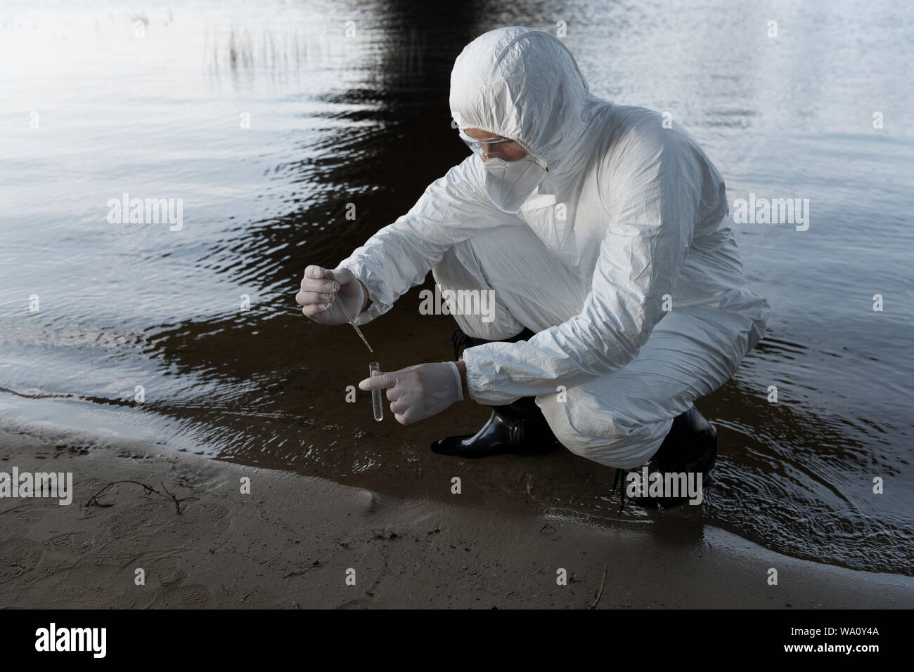 water inspector in protective costume and respirator taking water ...