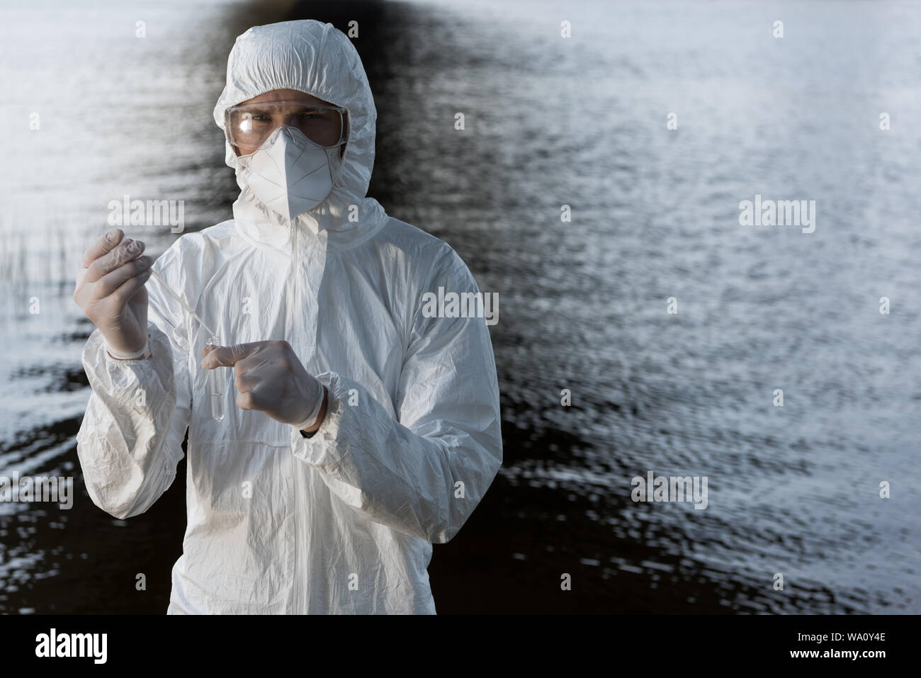 water inspector in protective costume, goggles and respirator taking ...