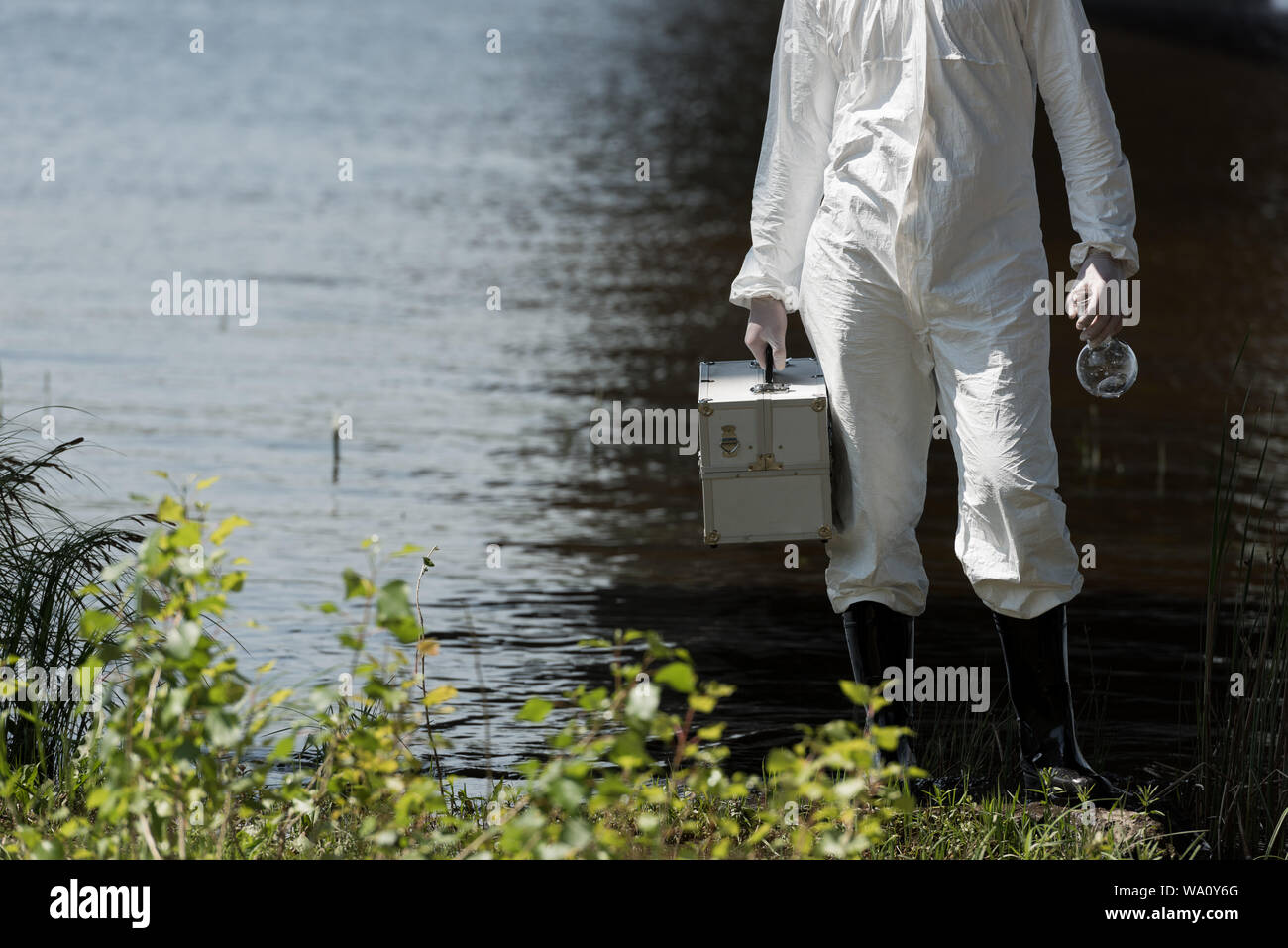 partial view of water inspector in protective costume holding ...