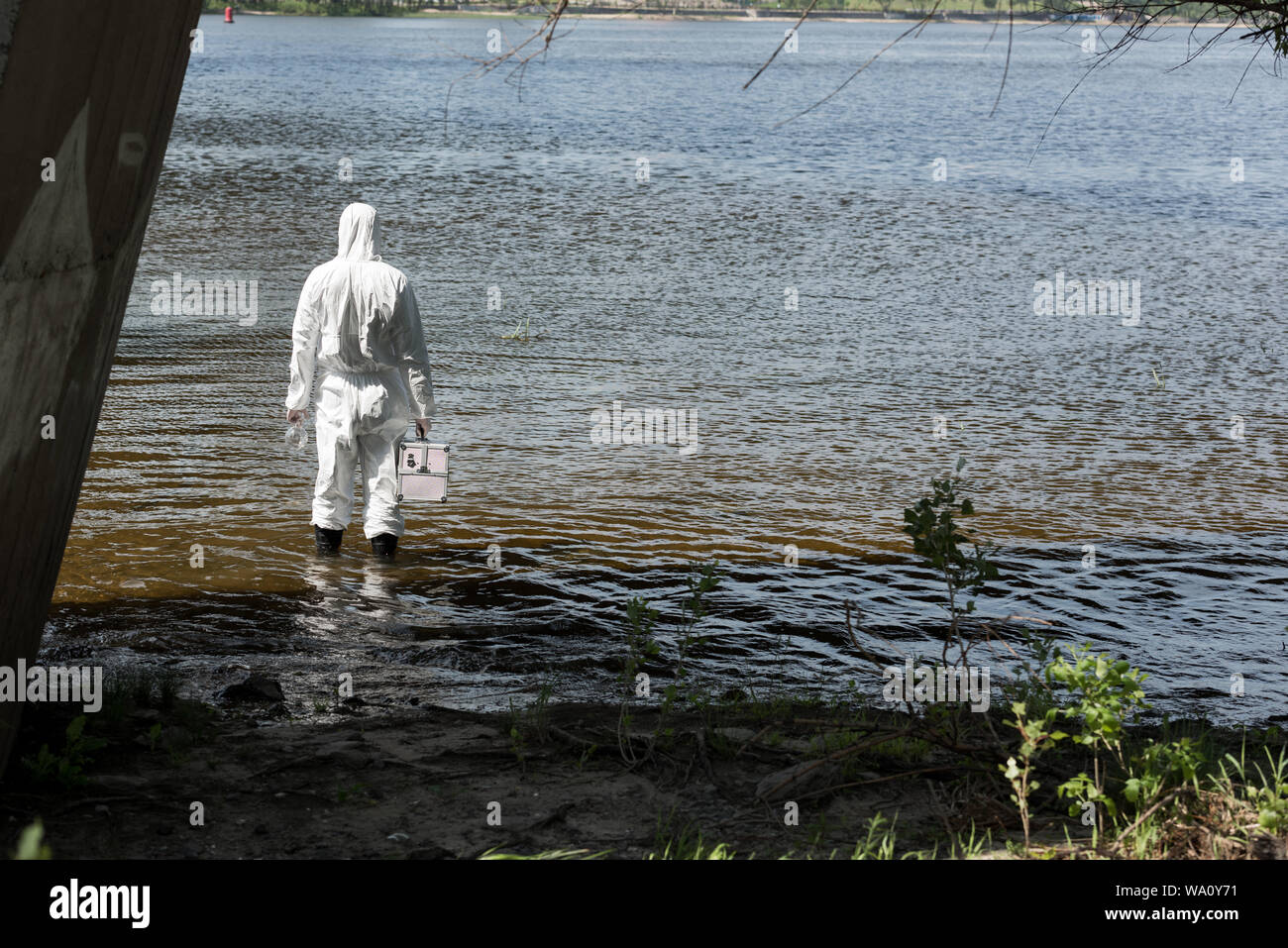 back view of water inspector in protective costume holding inspection ...