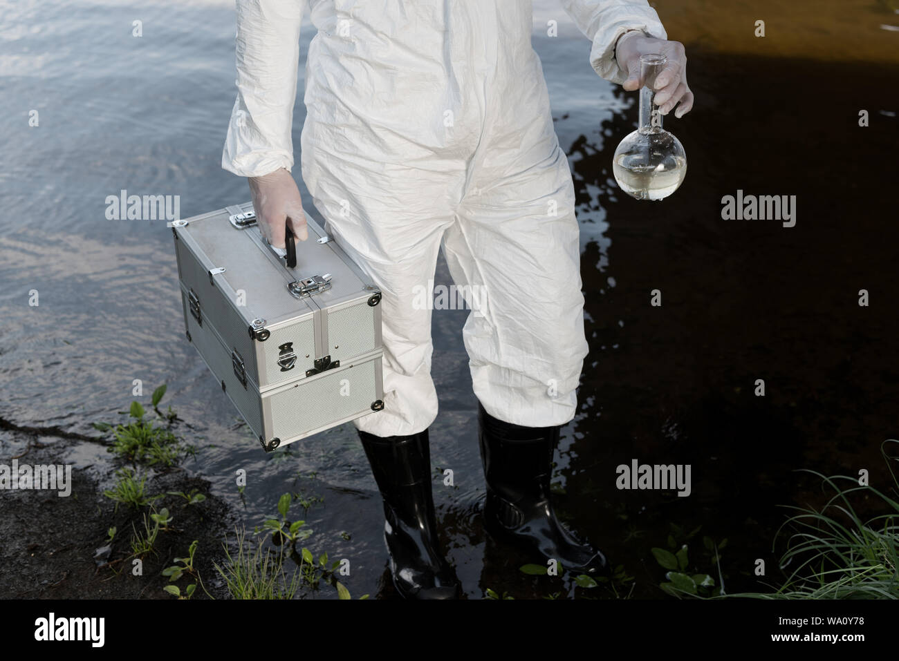 partial view of water inspector in protective costume holding ...
