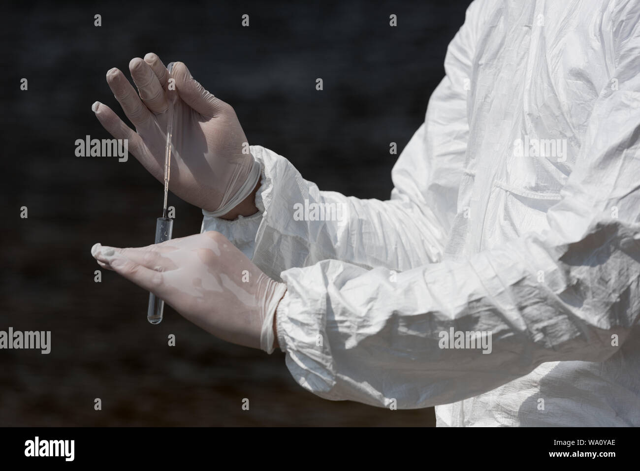 partial view of water inspector in latex gloves with test tube taking ...