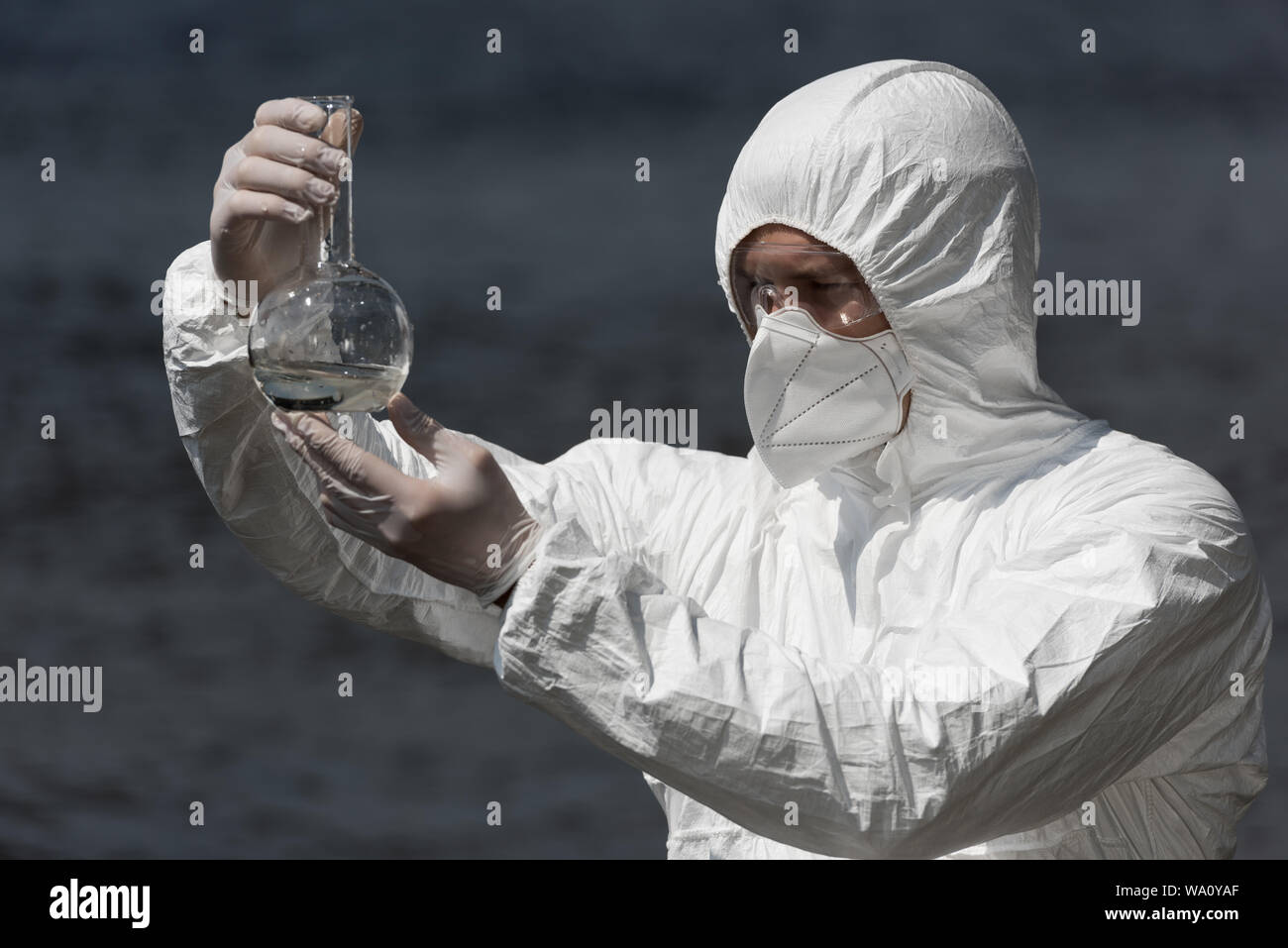 water inspector in protective costume, respirator and goggles holding ...