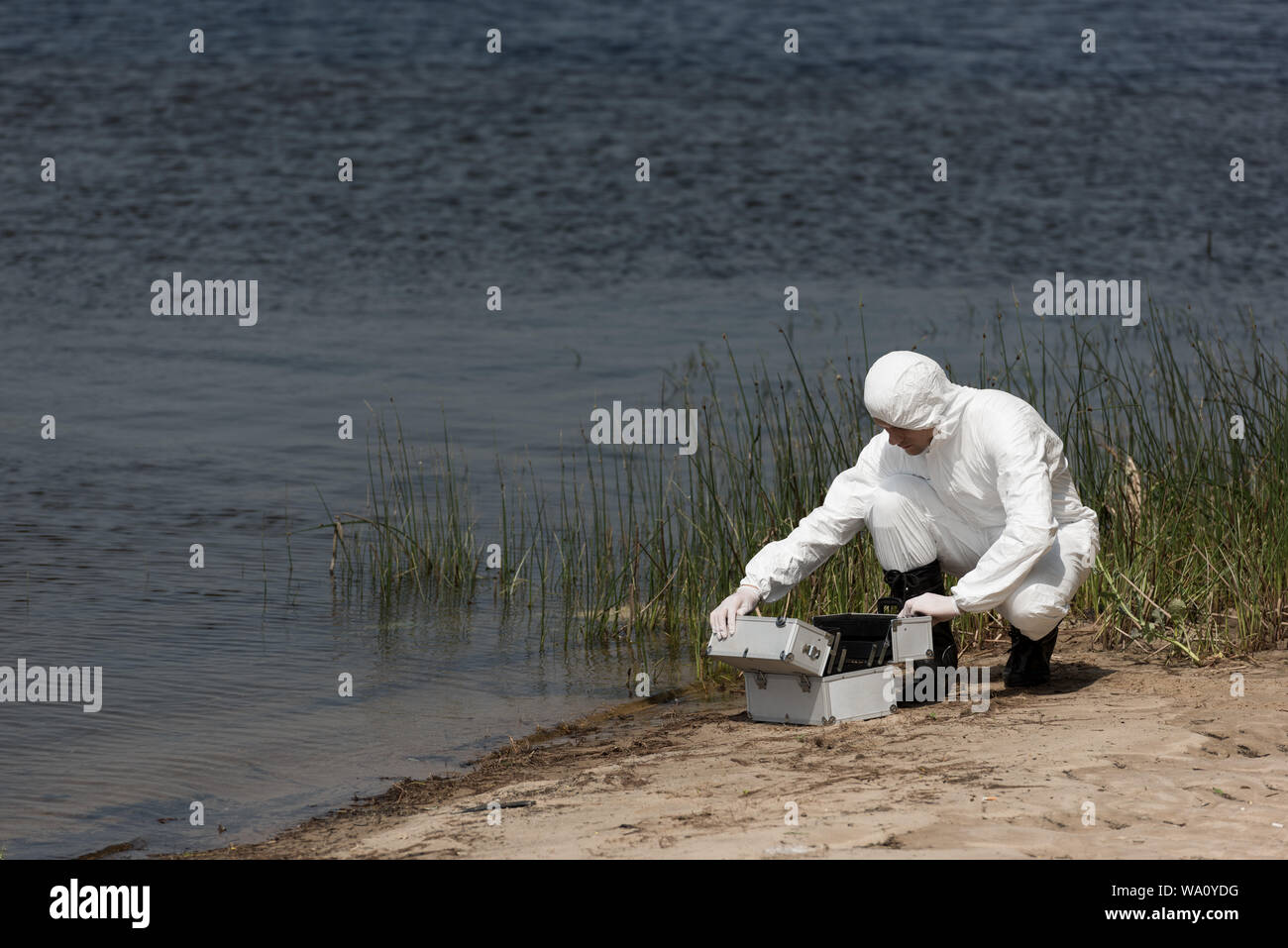 water inspector in protective costume with inspection kit sitting on ...