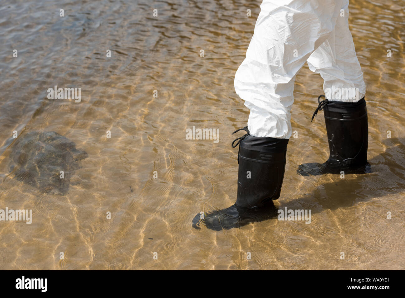 cropped view of water inspector in protective costume and boots ...