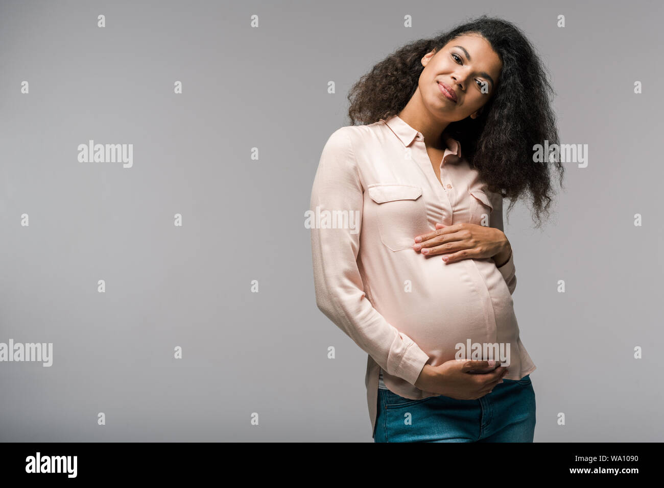 Smiling Young Pregnant African American Woman Touching Belly While
