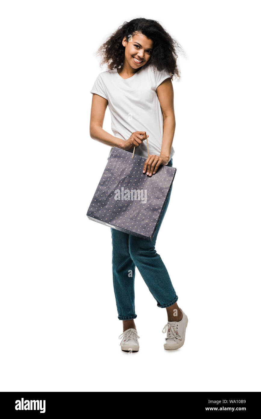 happy african american girl holding shopping bag while standing ...