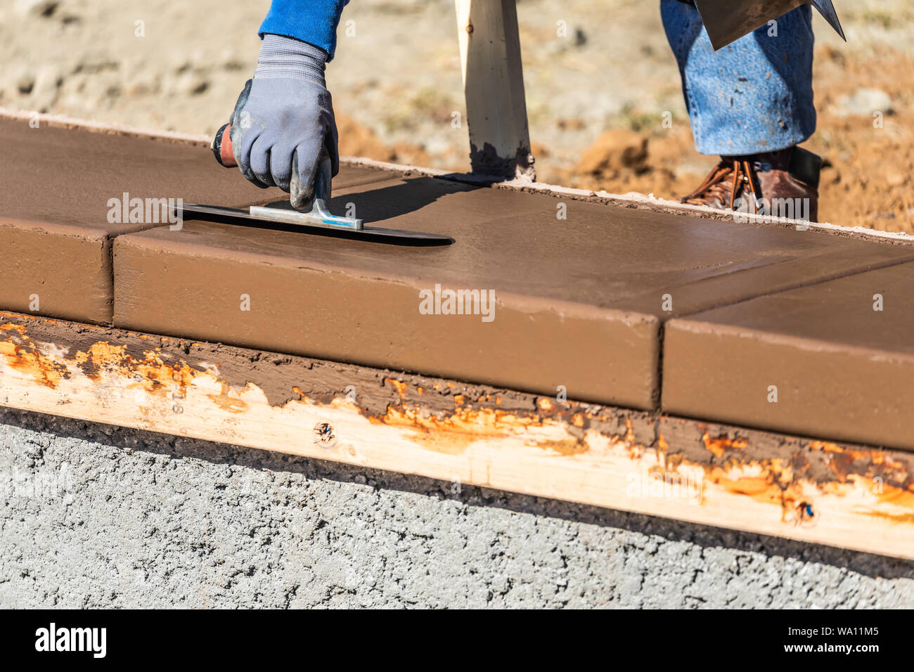 Construction Worker Using Trowel On Wet Cement Forming Coping Around ...