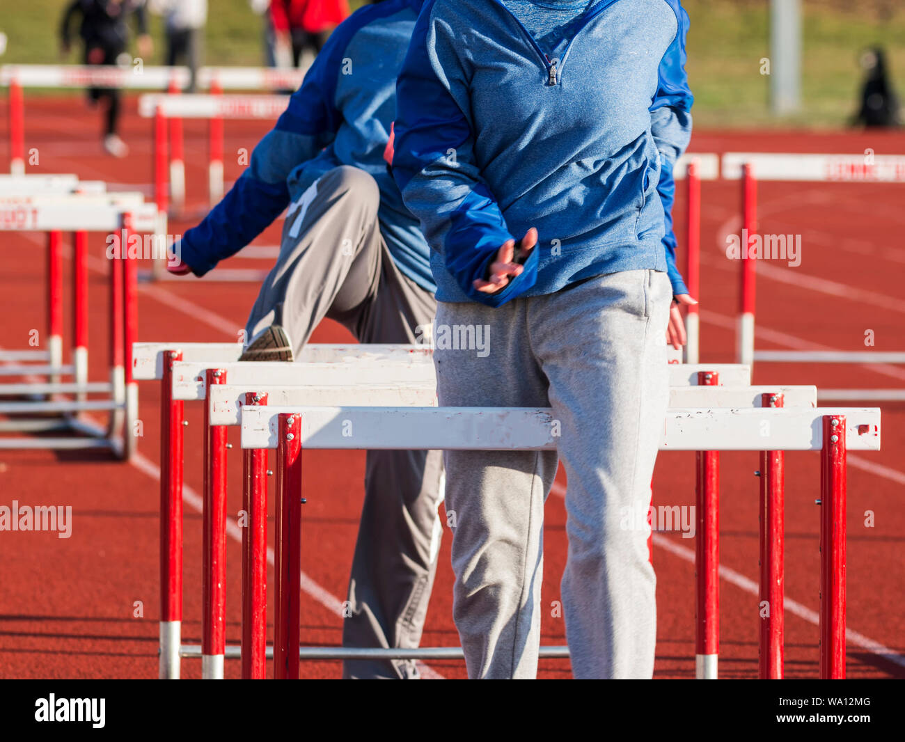 Two high school girls doing hurdle walk over drills in the sweats while ...