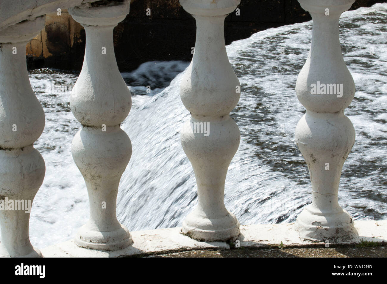 view of a water fall from the side through the railing of the staircase ...