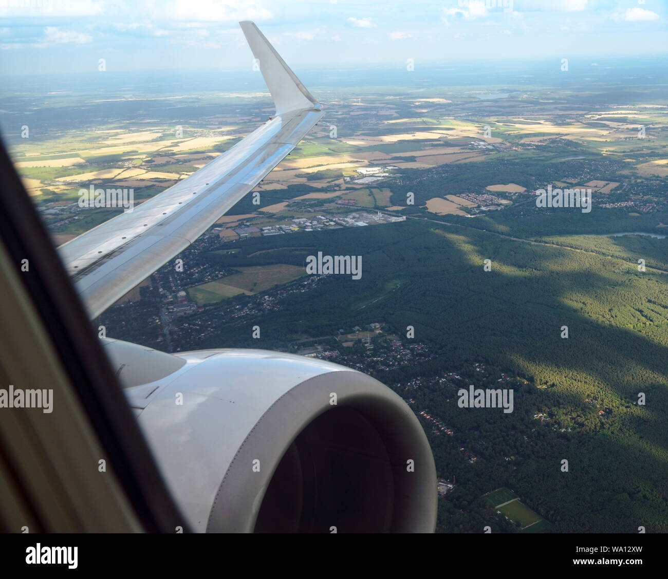 view through an airplane window to the wing and the jet engine over an ...