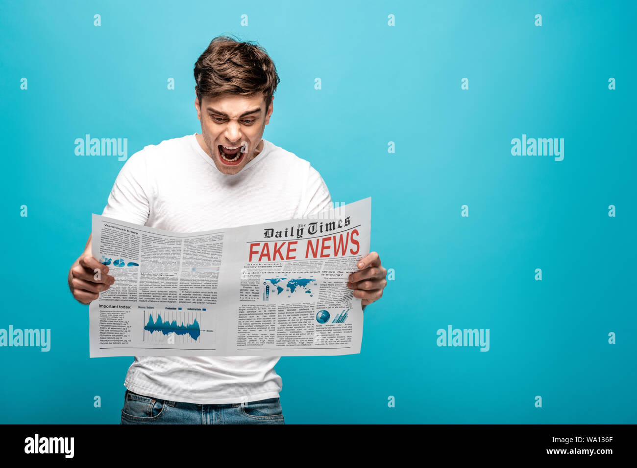 angry man yelling while reading newspaper with fake news on blue ...