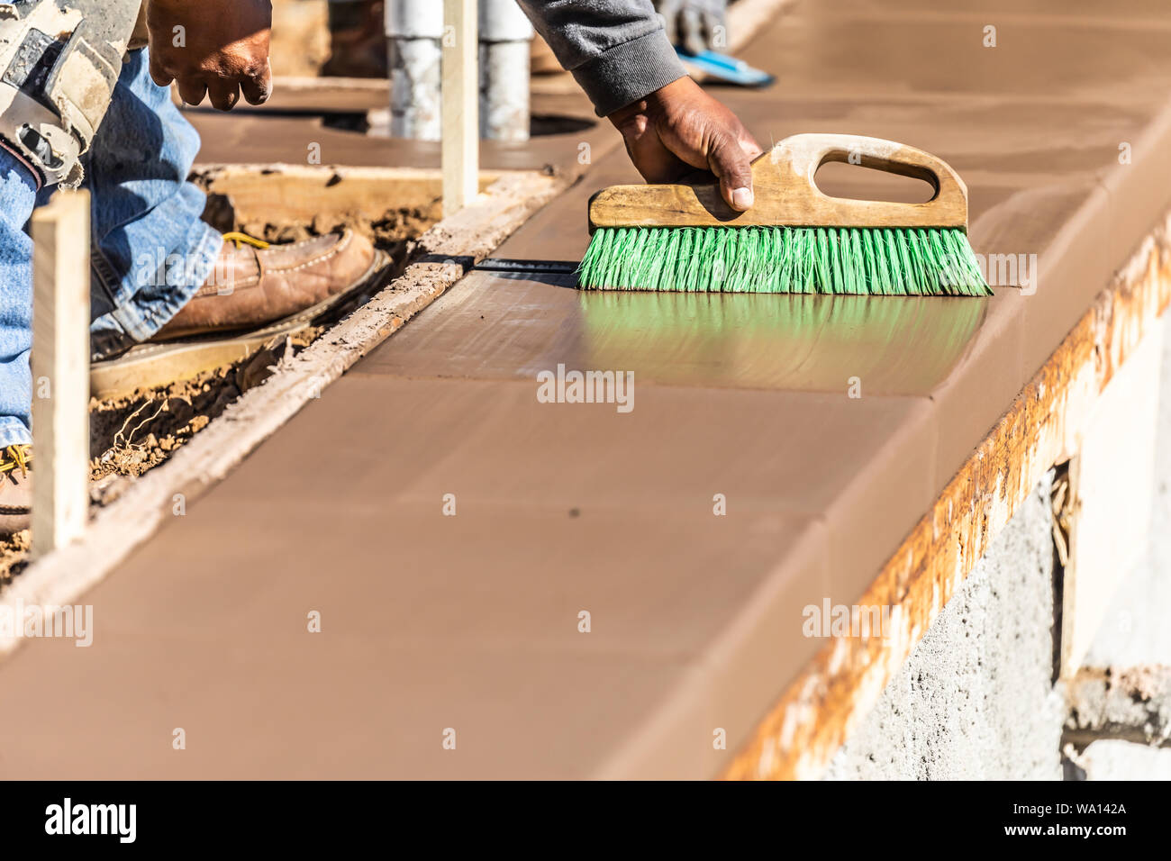 Construction Worker Using Brush On Wet Cement Forming Coping Around New ...