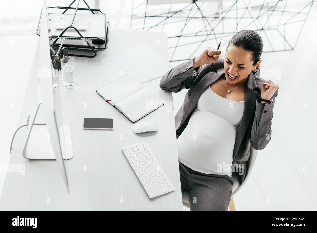 pregnant woman sitting behind table and screaming because of pain Stock ...