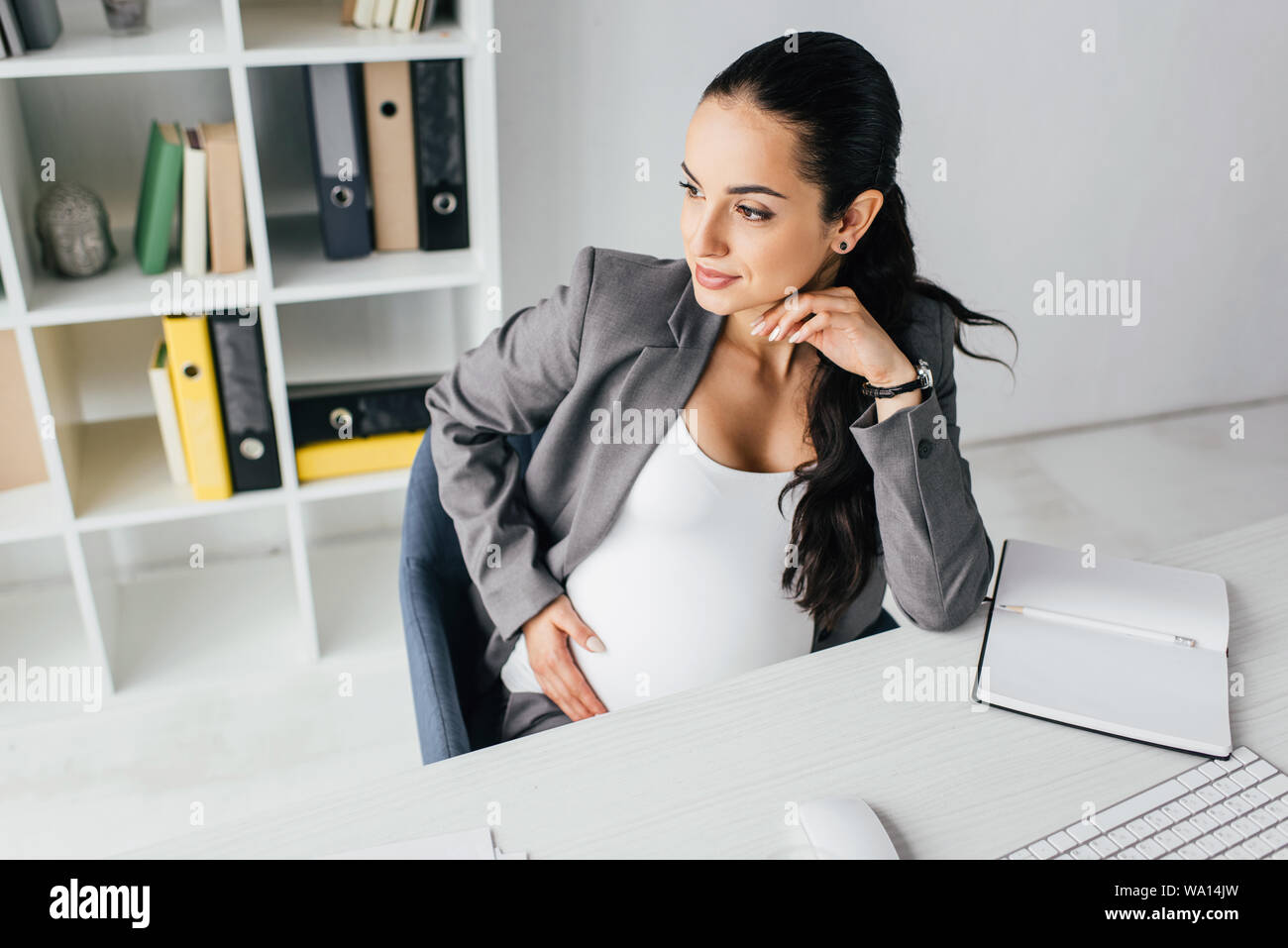pregnant woman sitting behind table and looking away Stock Photo - Alamy