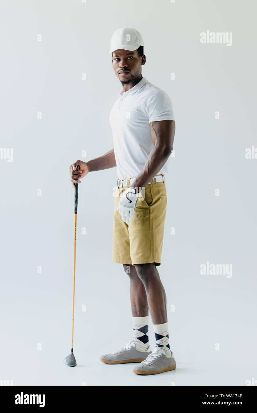 handsome african american sportsman holding golf club on grey ...