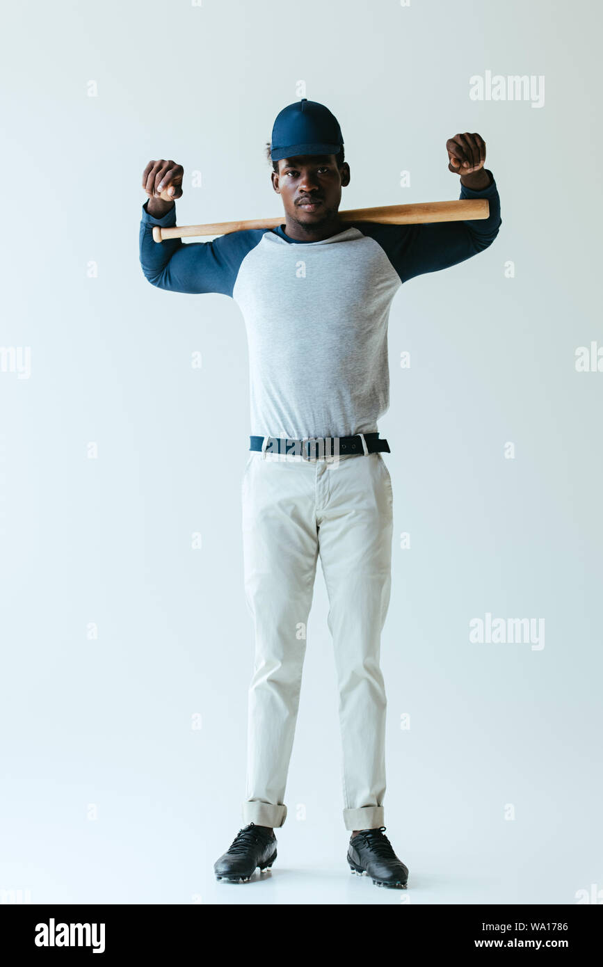 confident african american baseball player looking at camera on grey ...