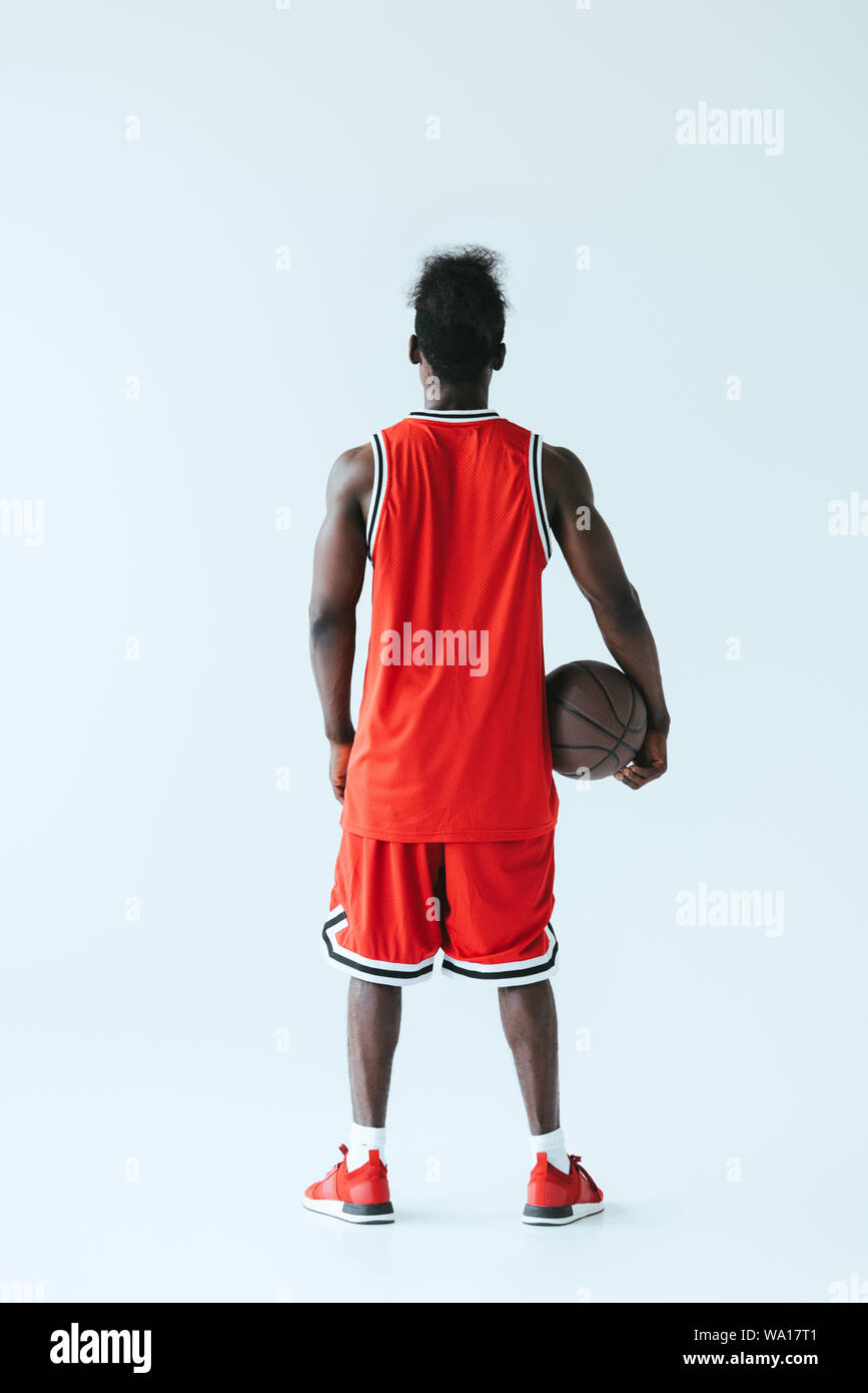 back view of african american basketball player holding ball on grey ...